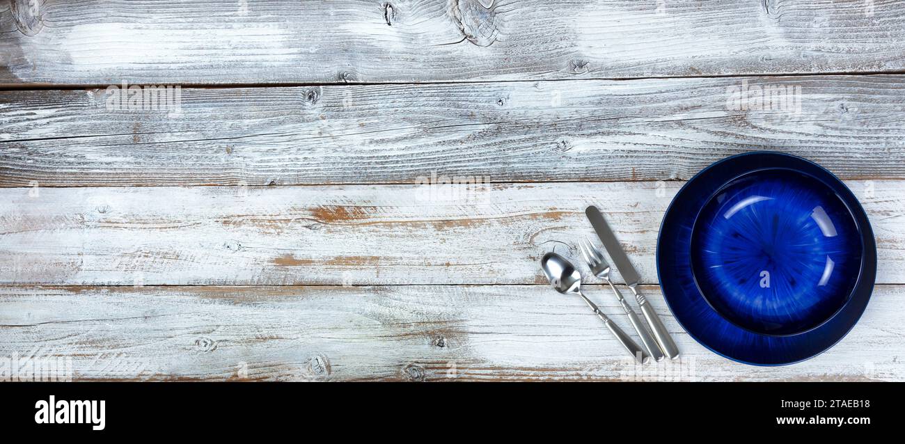 Simple dinner table setting of an empty main dark blue dish and bowl ...