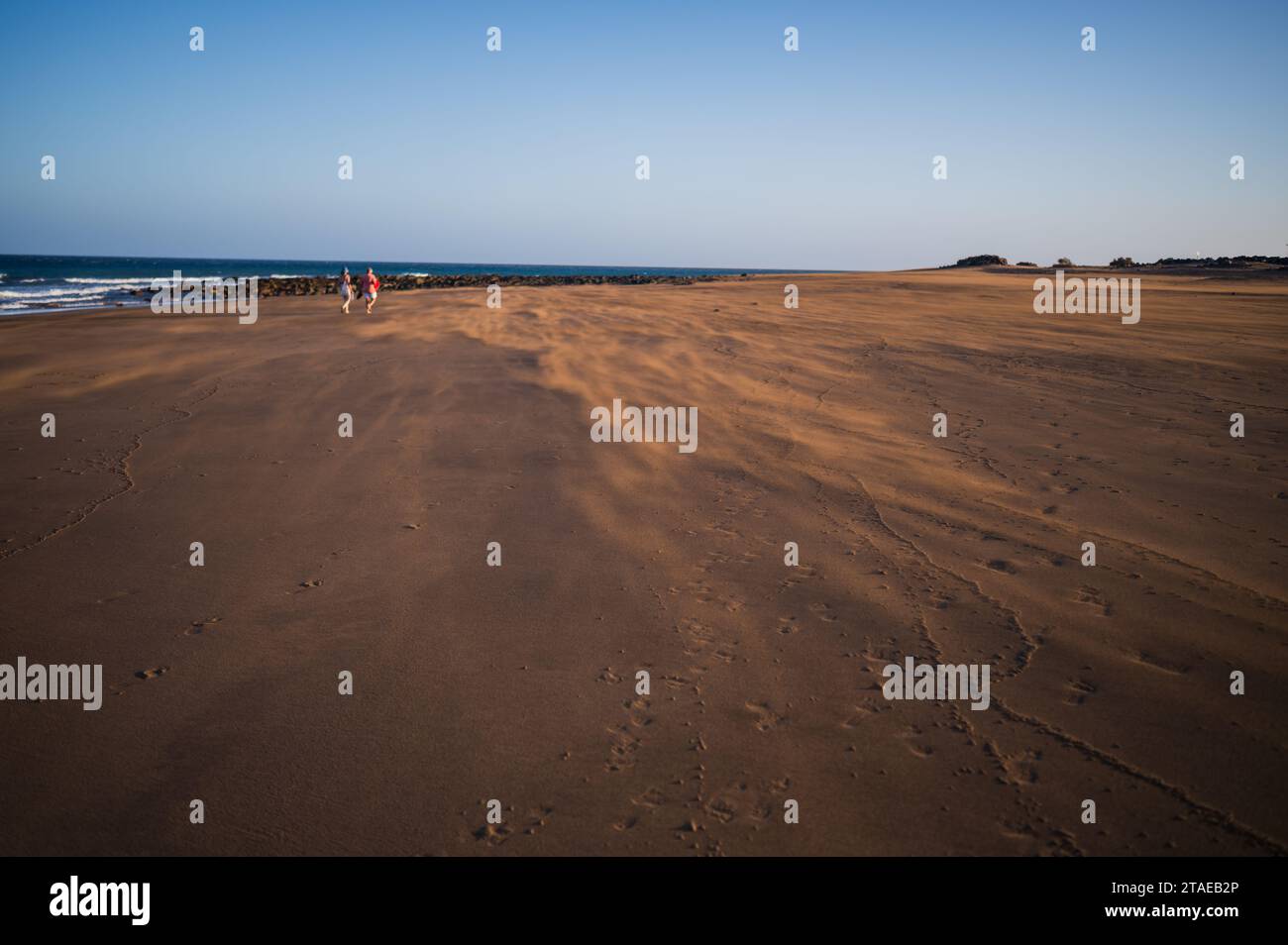 Couple walks on the beach as a strong wind blows sand in Lanzarote ...