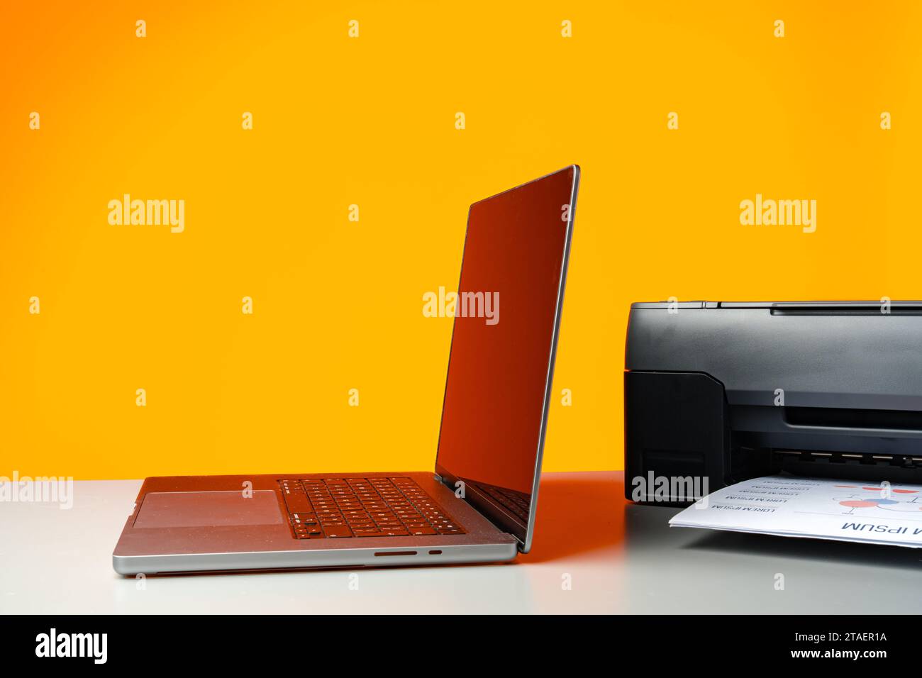 Laser printer and laptop on desk against yellow background Stock Photo ...