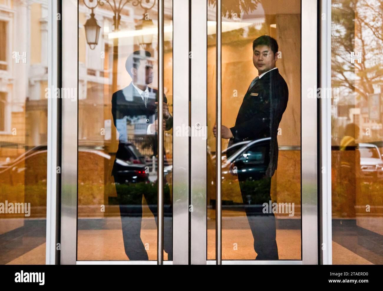 Doormen standing behind luxury hotel's doors in Hanoi, Vietnam, Asia ...