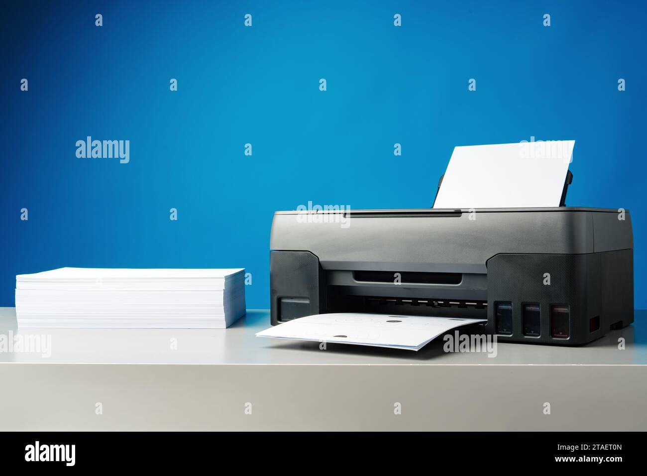 Laser printer on desk against blue background Stock Photo - Alamy