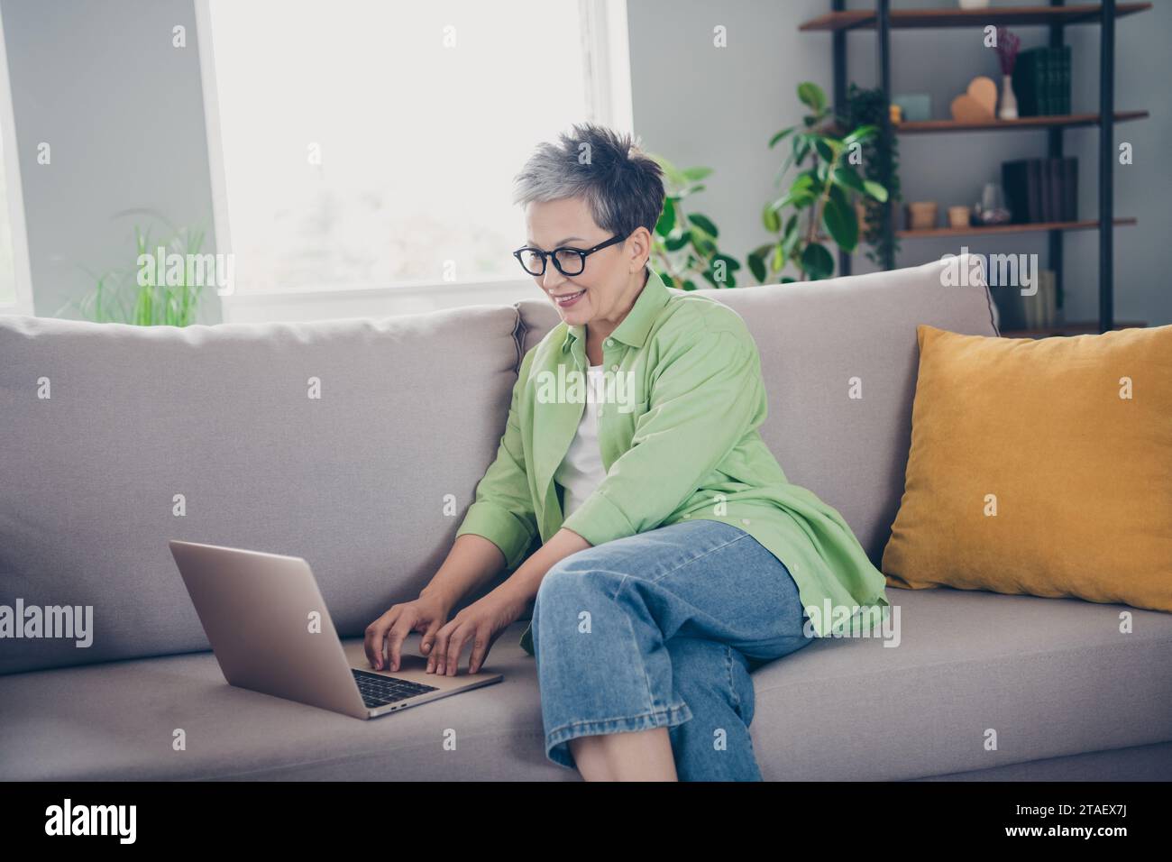 Photo of smiling aged gray haired woman sitting couch programmer on ...