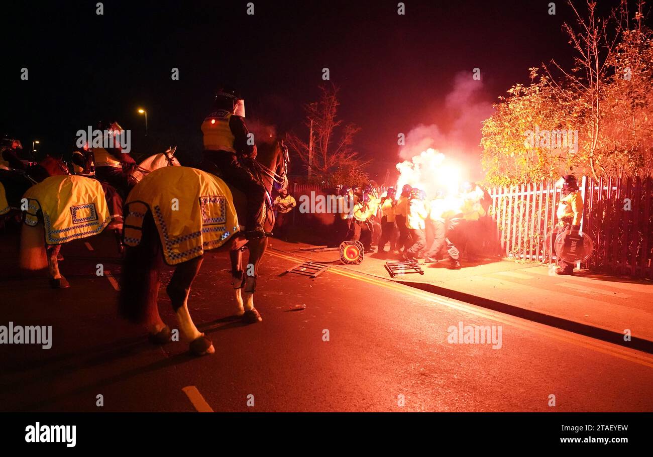 Police attempt to put out flares that have thrown towards them outside ...