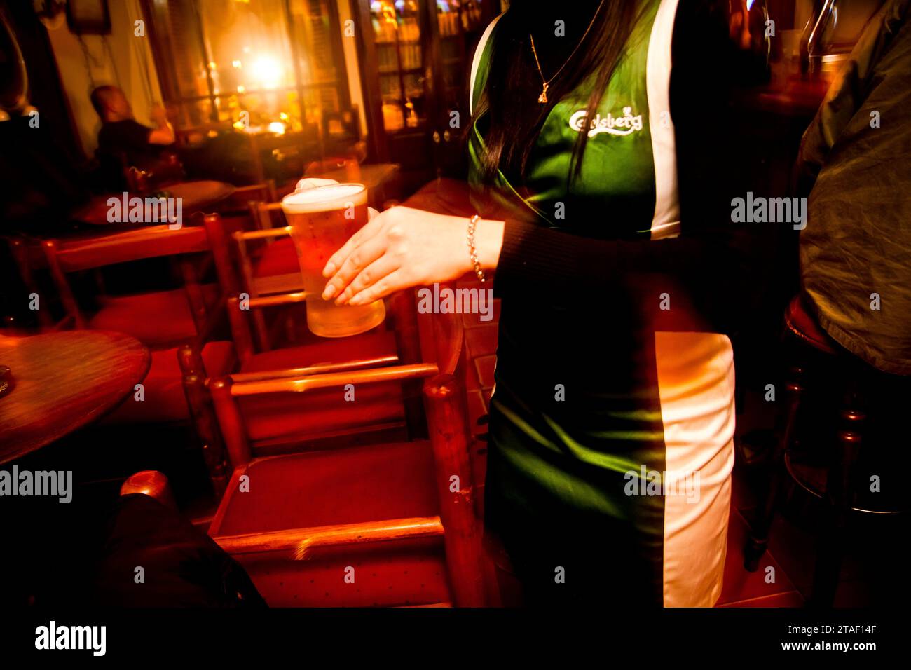 A Carlsberg beer promotion girl carries a beer to a customer in a bar ...