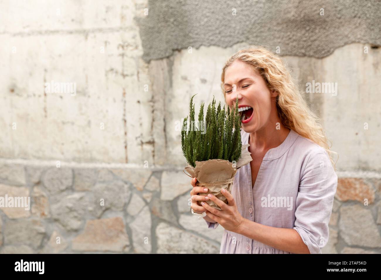 Angry woman holds plant in front of her face and screaming at it Stock ...
