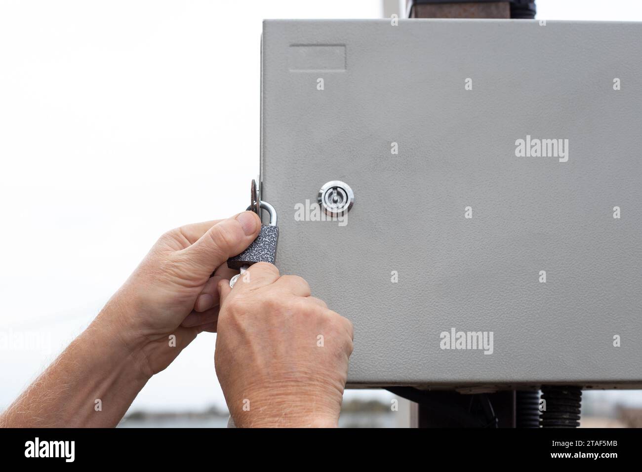 An electrician locks an electrical panel with automatic switches ...