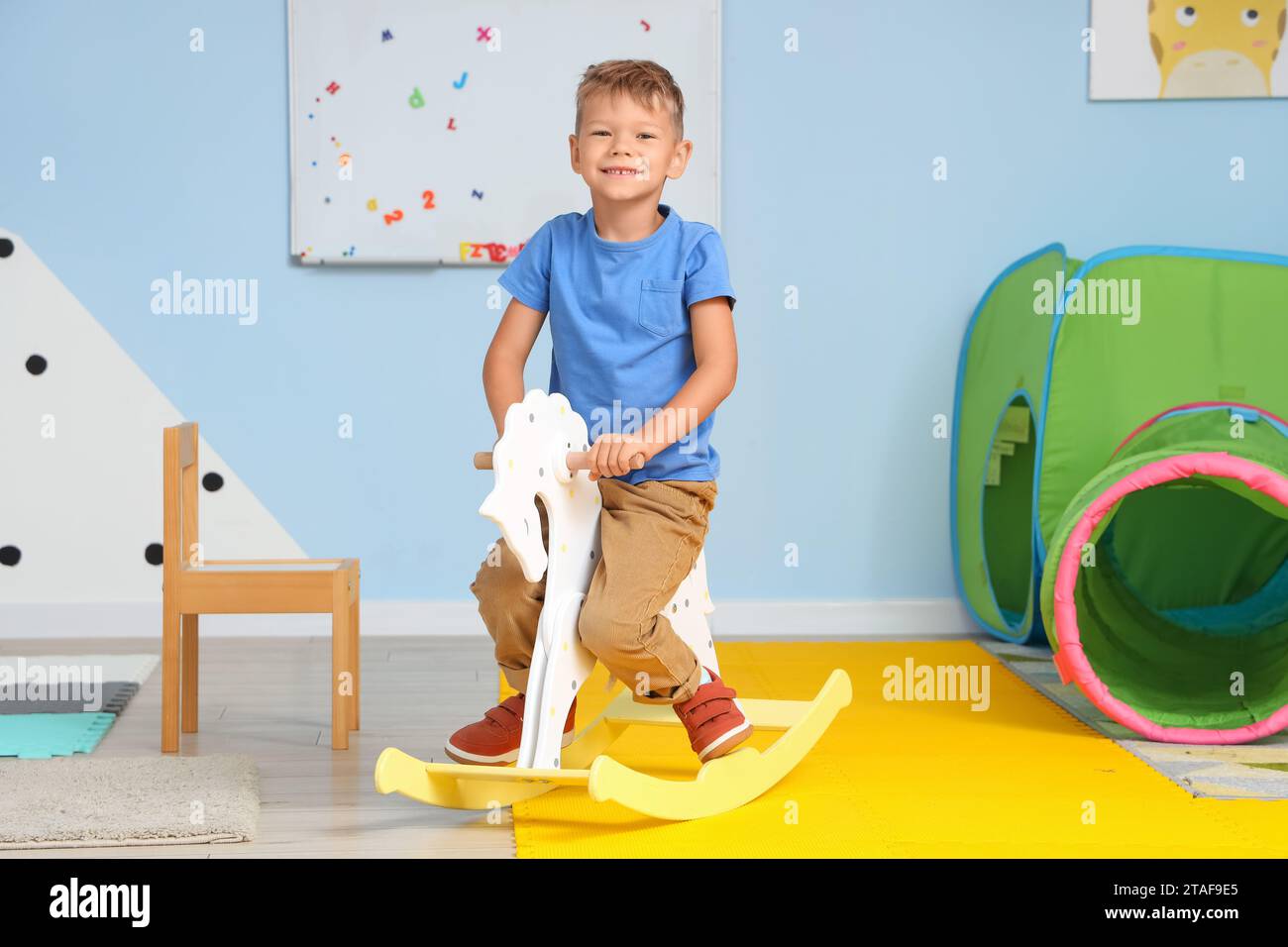 Cute little boy playing with rocking horse in kindergarten Stock Photo ...