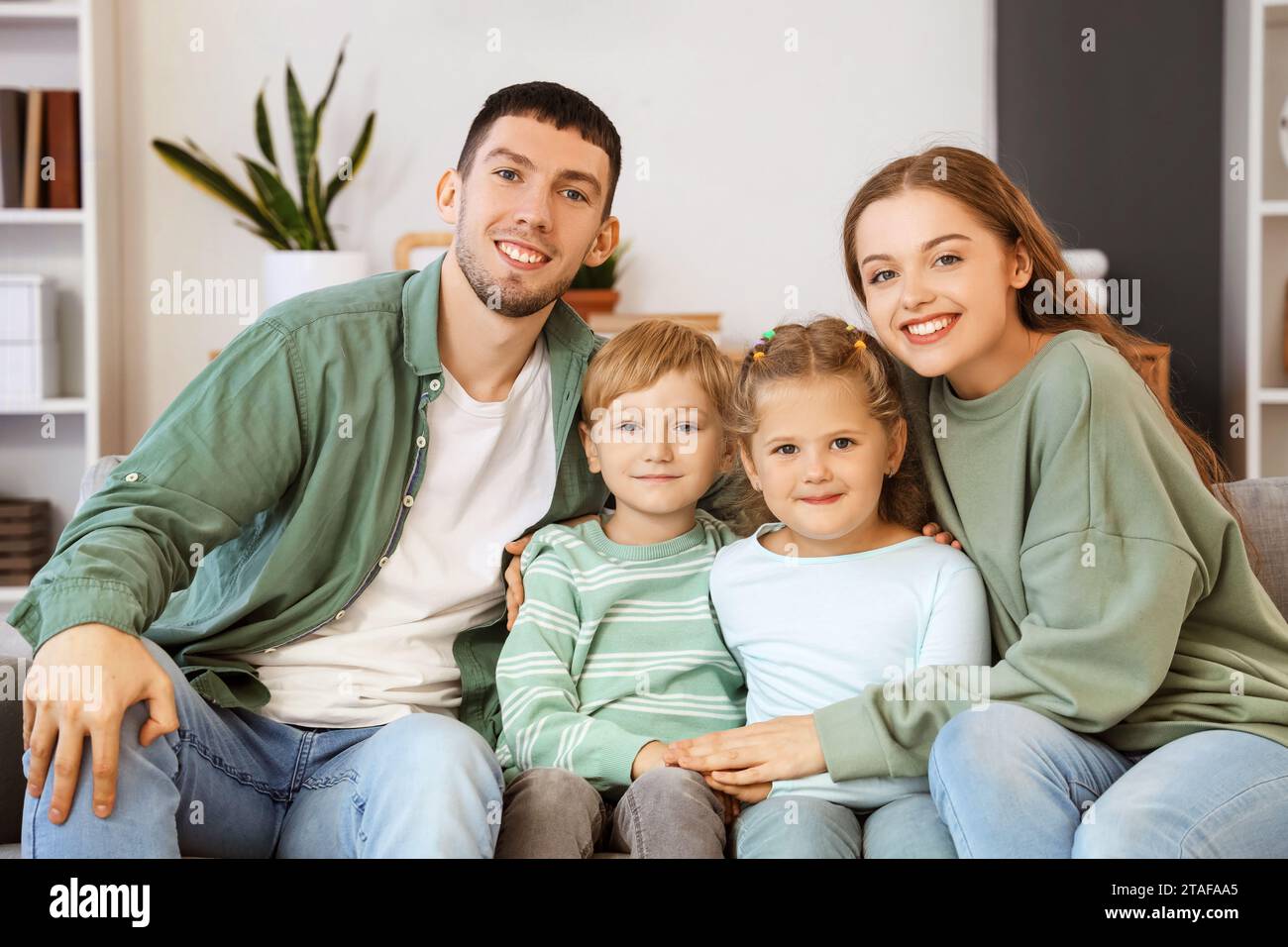 Little children with their parents sitting on sofa at home Stock Photo ...