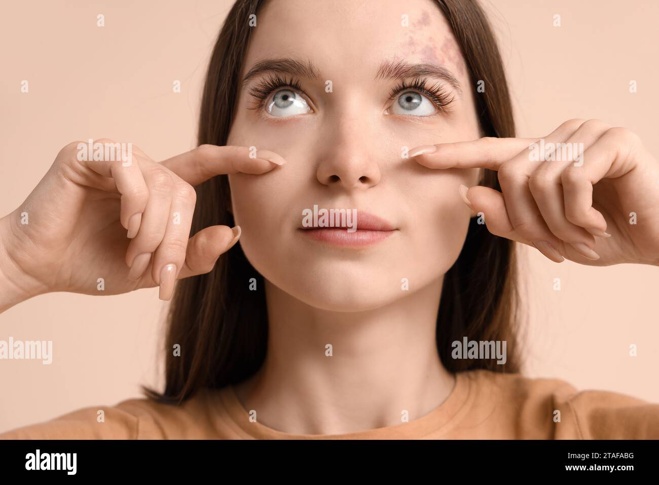 Young woman doing face building exercise on beige background, closeup ...
