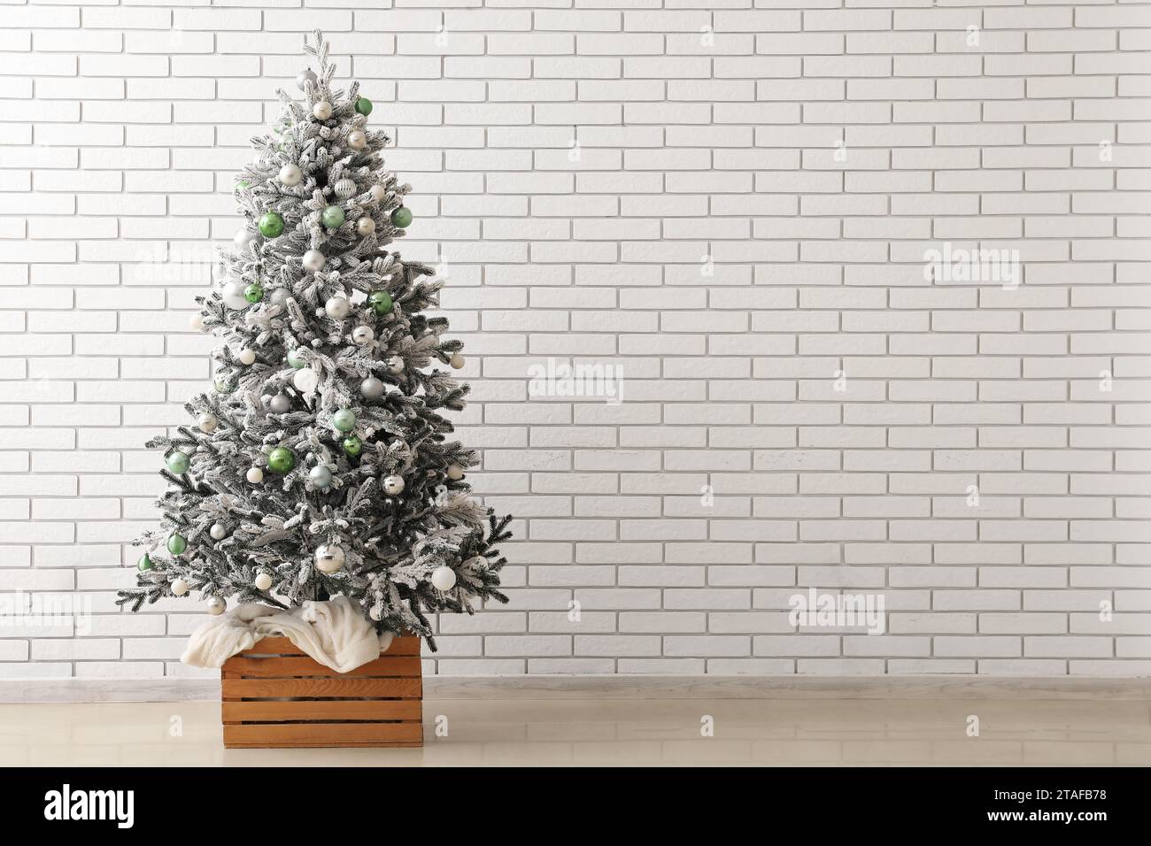Beautiful Christmas tree against light brick wall Stock Photo - Alamy