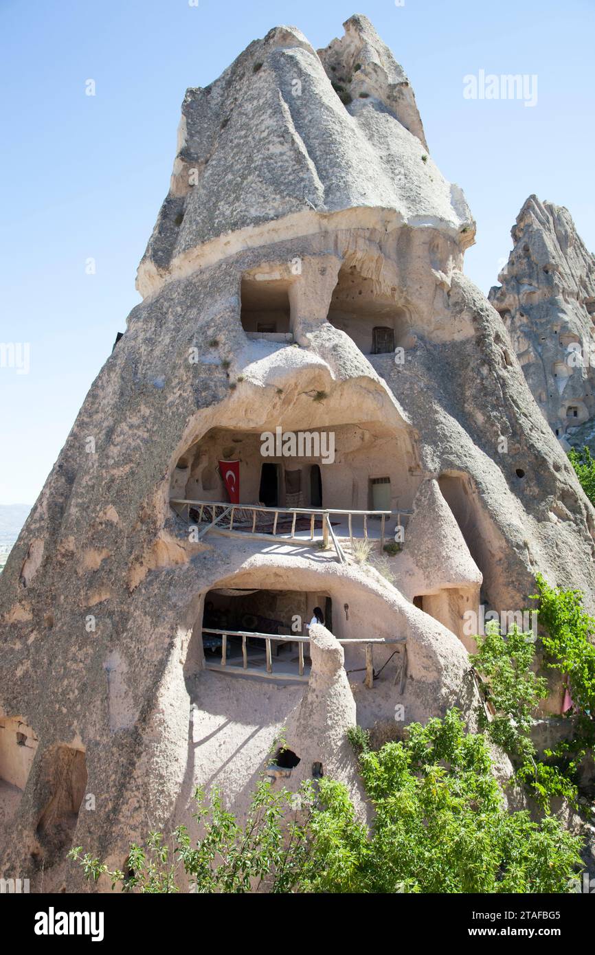 The close view of a tall eroded rock with carved living spaces inside ...
