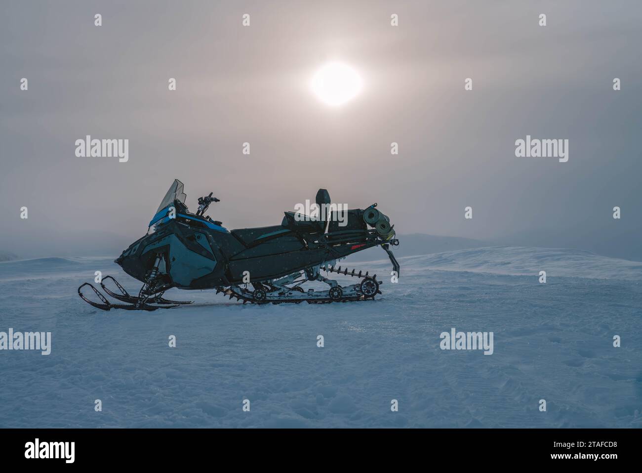Nice side view at snowmobile stands at mountain top under frosty winter ...
