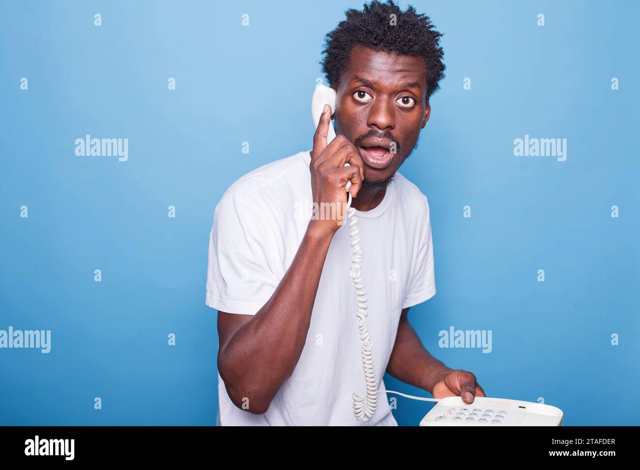 Surprised young black man with afro hair speaks on a telephone in a ...