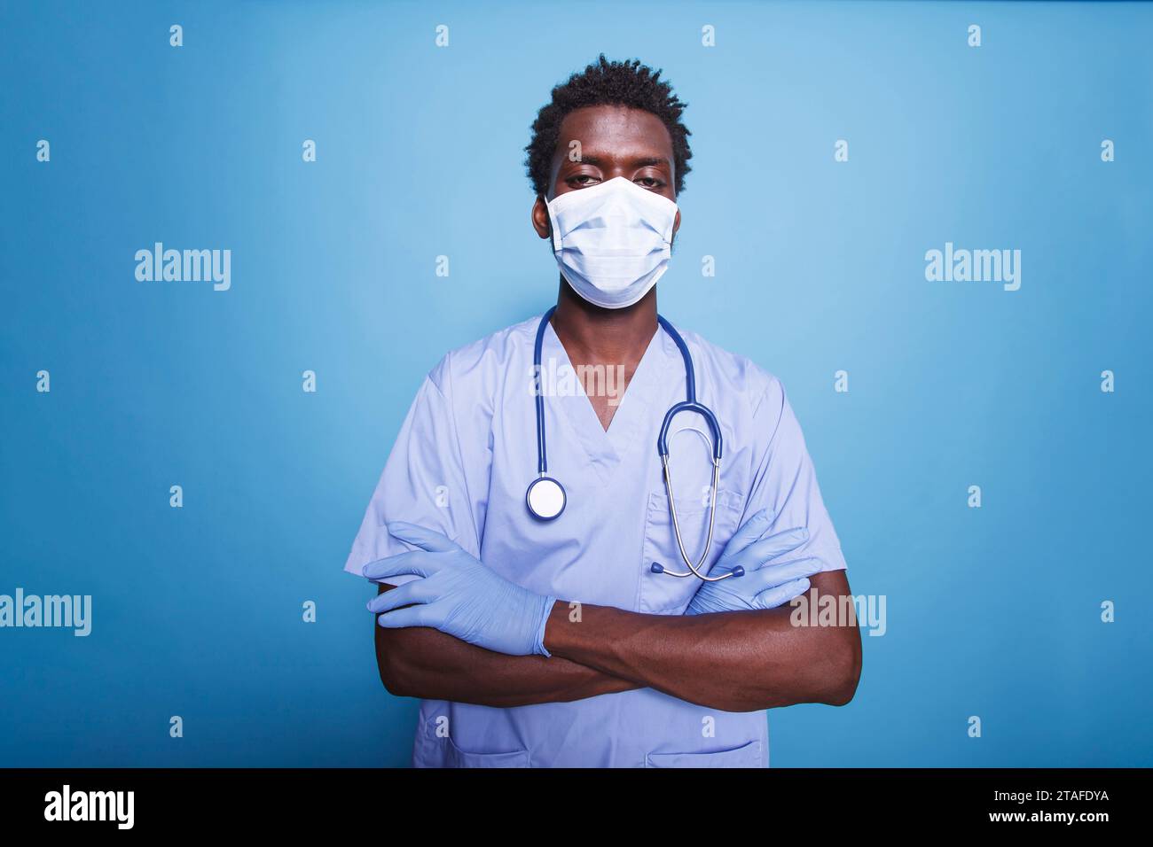Portrait of a black nurse practitioner posing with his arms crossed on ...