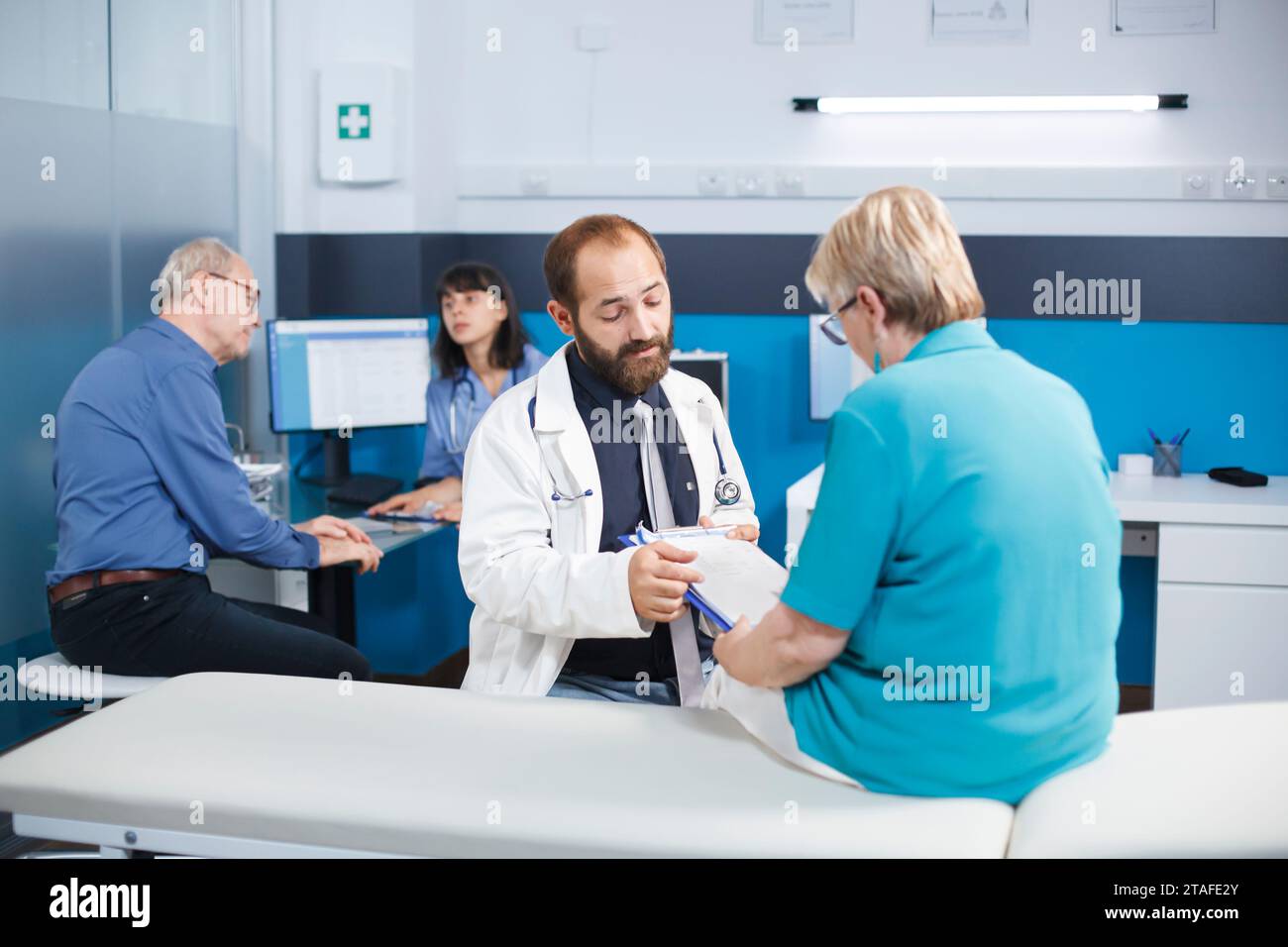 Old woman signing paperwork and speaking with doctor about prescription ...