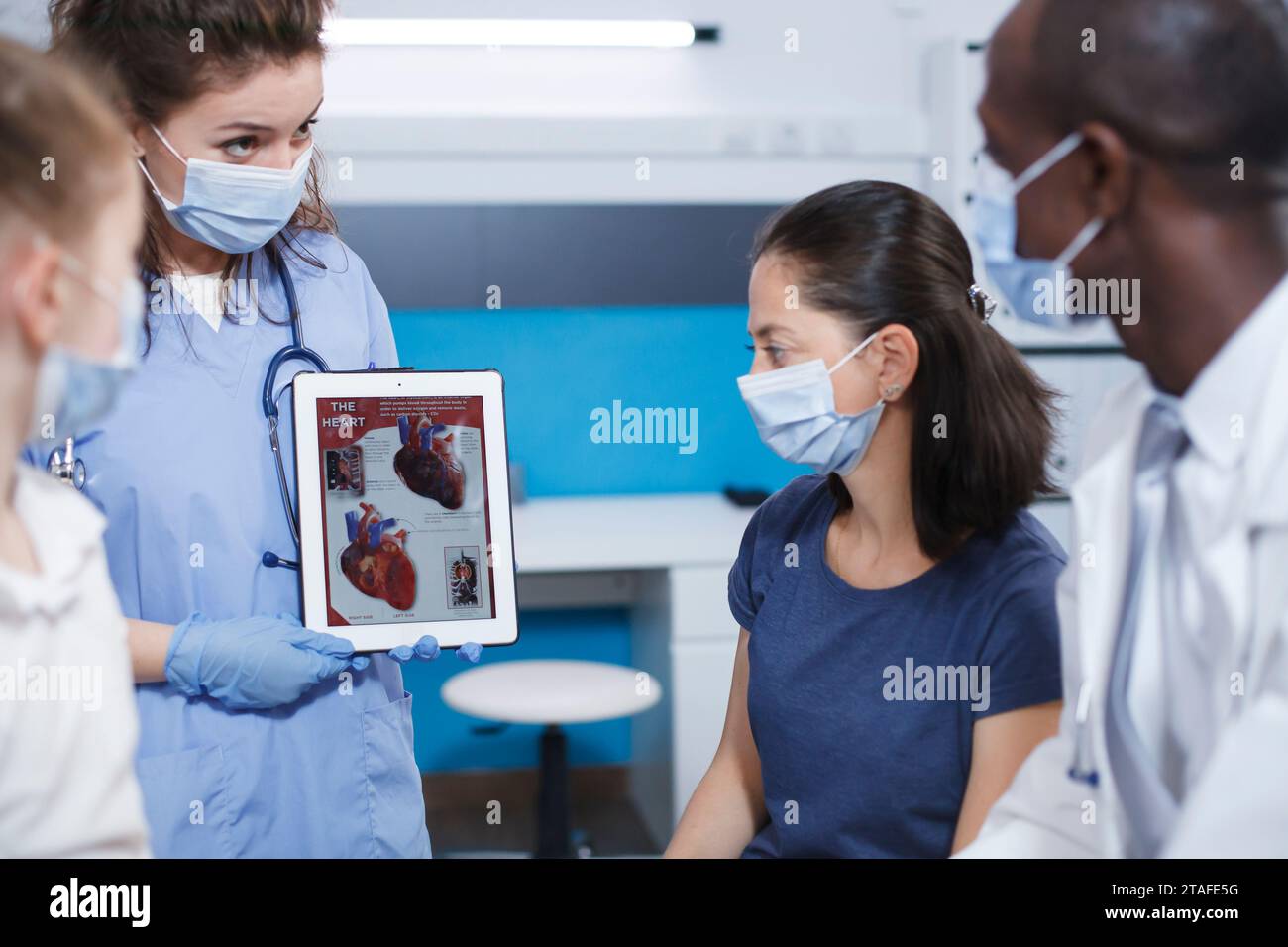 Detailed image of healthcare professionals using a tablet to explain to ...