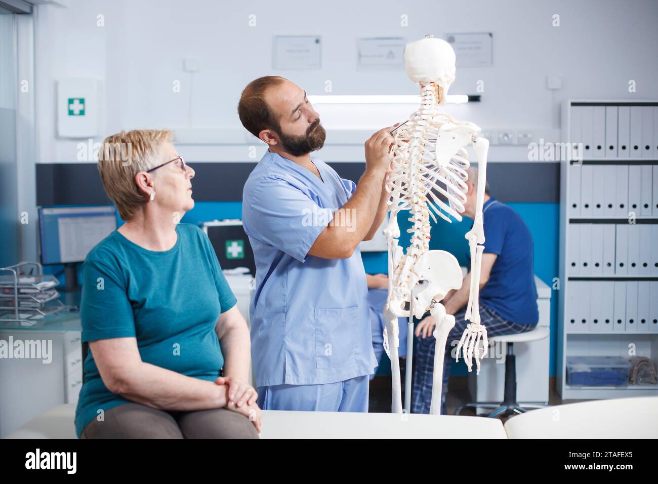 Nurse and retired patient looking at spinal cord on human skeleton for ...