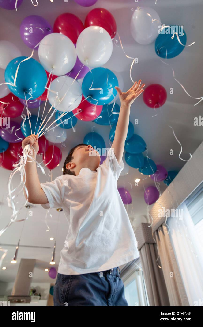 Boy reaching for balloons floating on the ceiling of a house Stock ...
