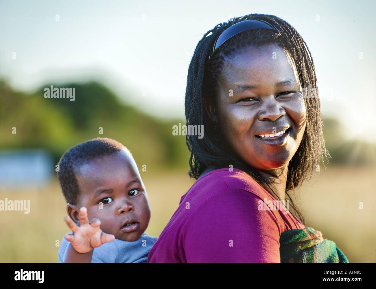 village african mother with braids carry child in the back wrapped in a ...