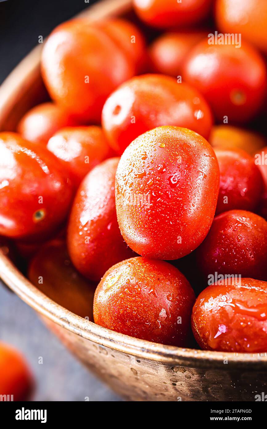 small red tomato, fresh vegetable used in Brazilian cuisine. Copper pot ...