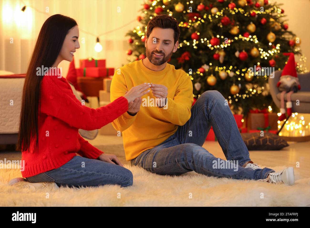 Making proposal. Man putting engagement ring on his girlfriend's finger ...