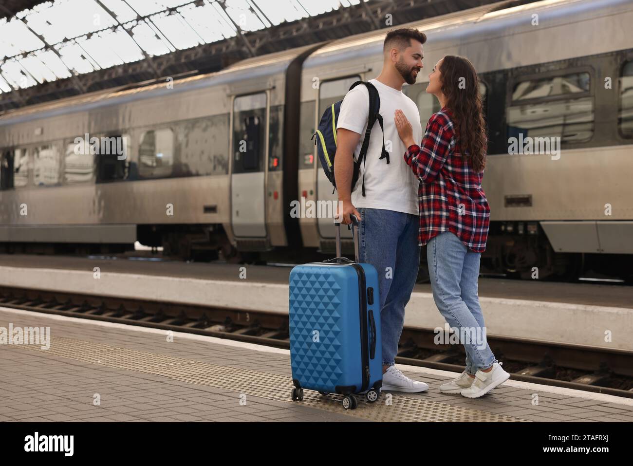 Long-distance relationship. Beautiful couple on platform of railway station, space for text ...