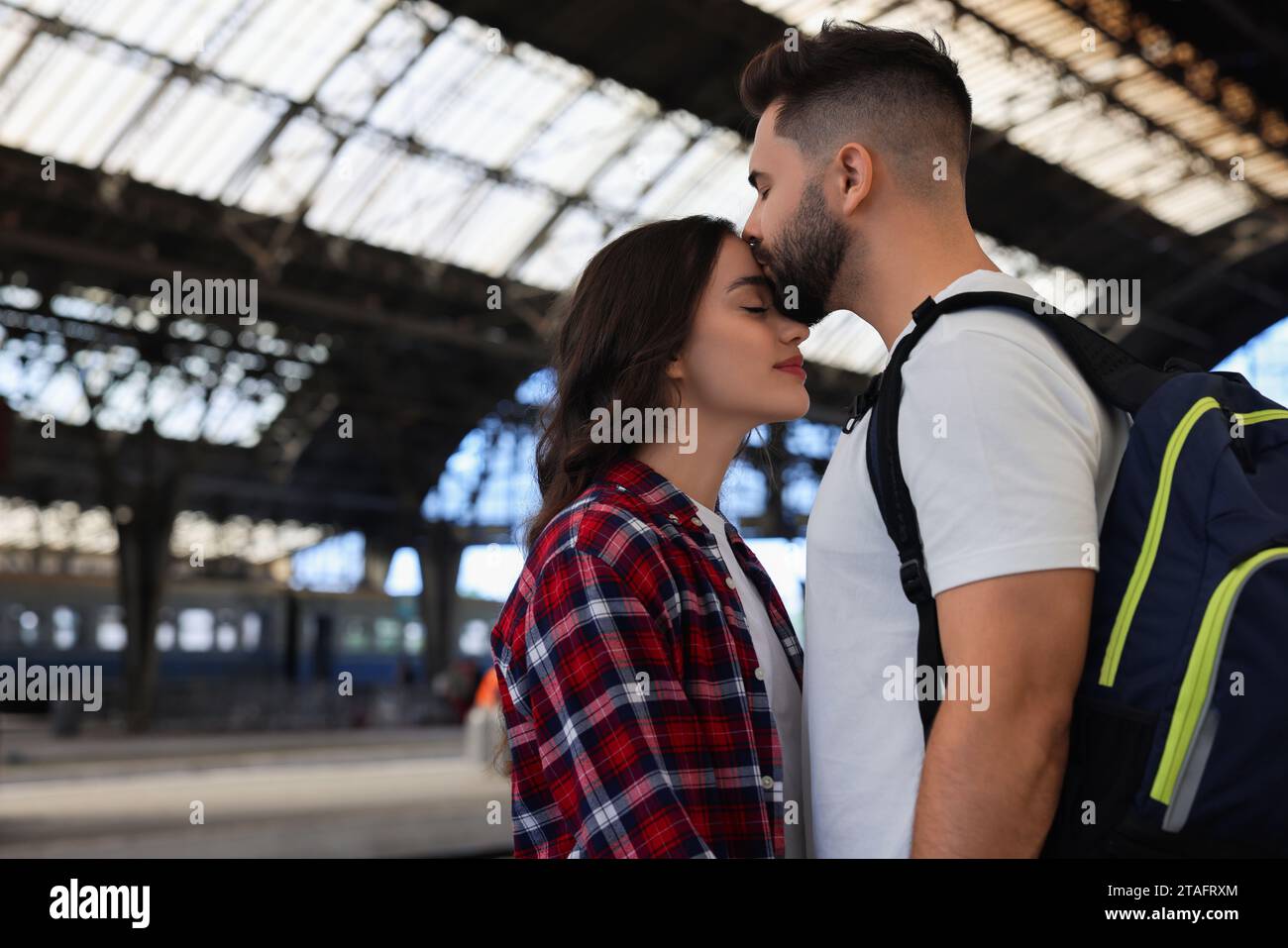 Long-distance relationship. Beautiful couple on platform of railway station, space for text ...
