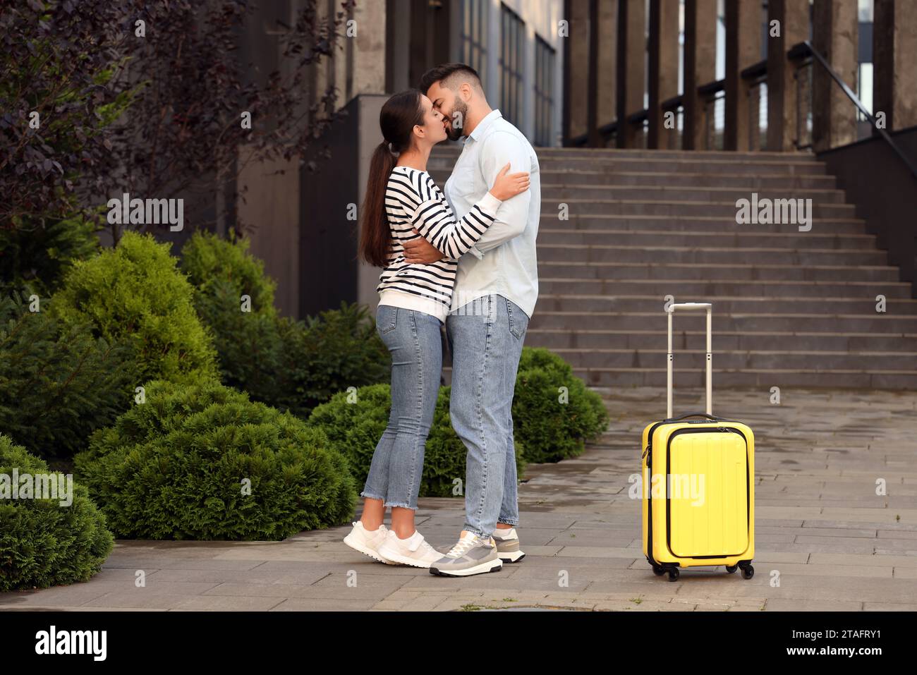 Long-distance relationship. Beautiful young couple kissing and suitcase ...