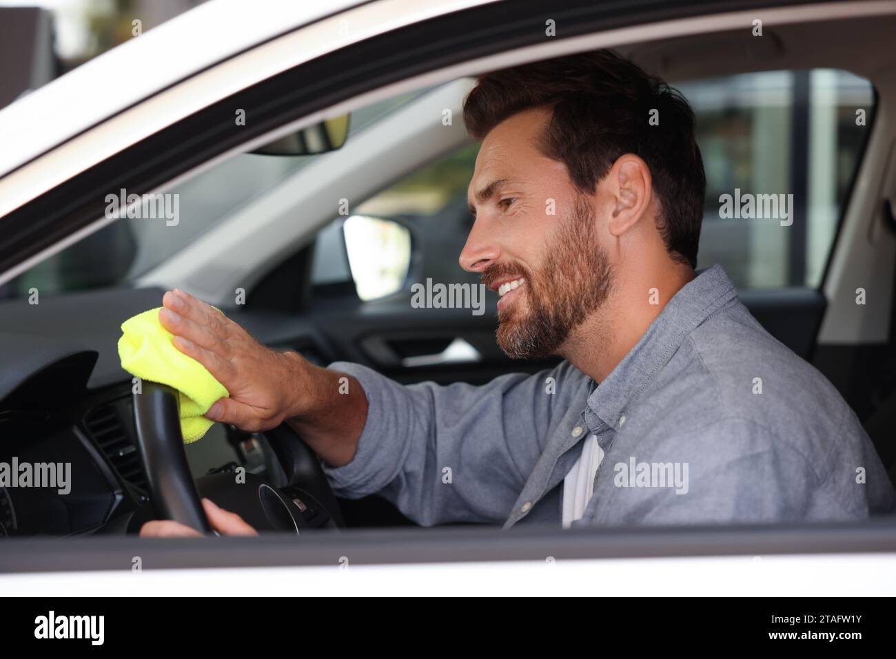 Man cleaning steering wheel with rag in car Stock Photo - Alamy
