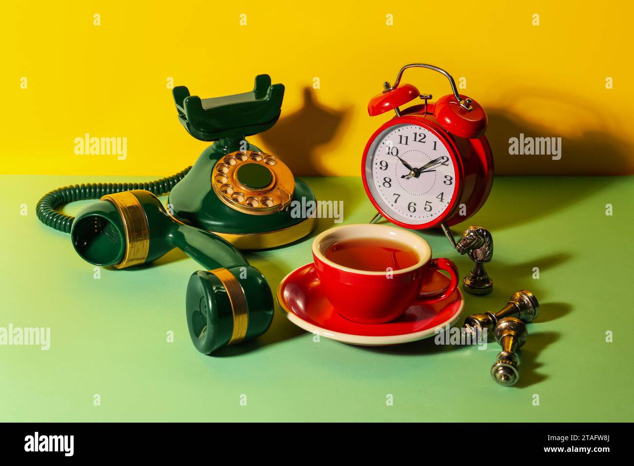Red cup of tea, alarm clock, vintage telephone and chessmen on light ...