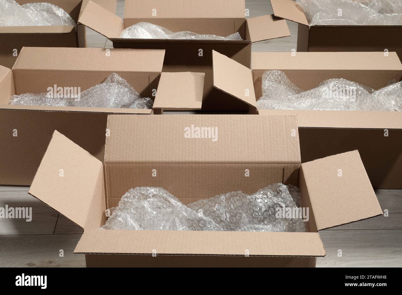 Many open cardboard boxes with bubble wrap on white wooden floor Stock ...