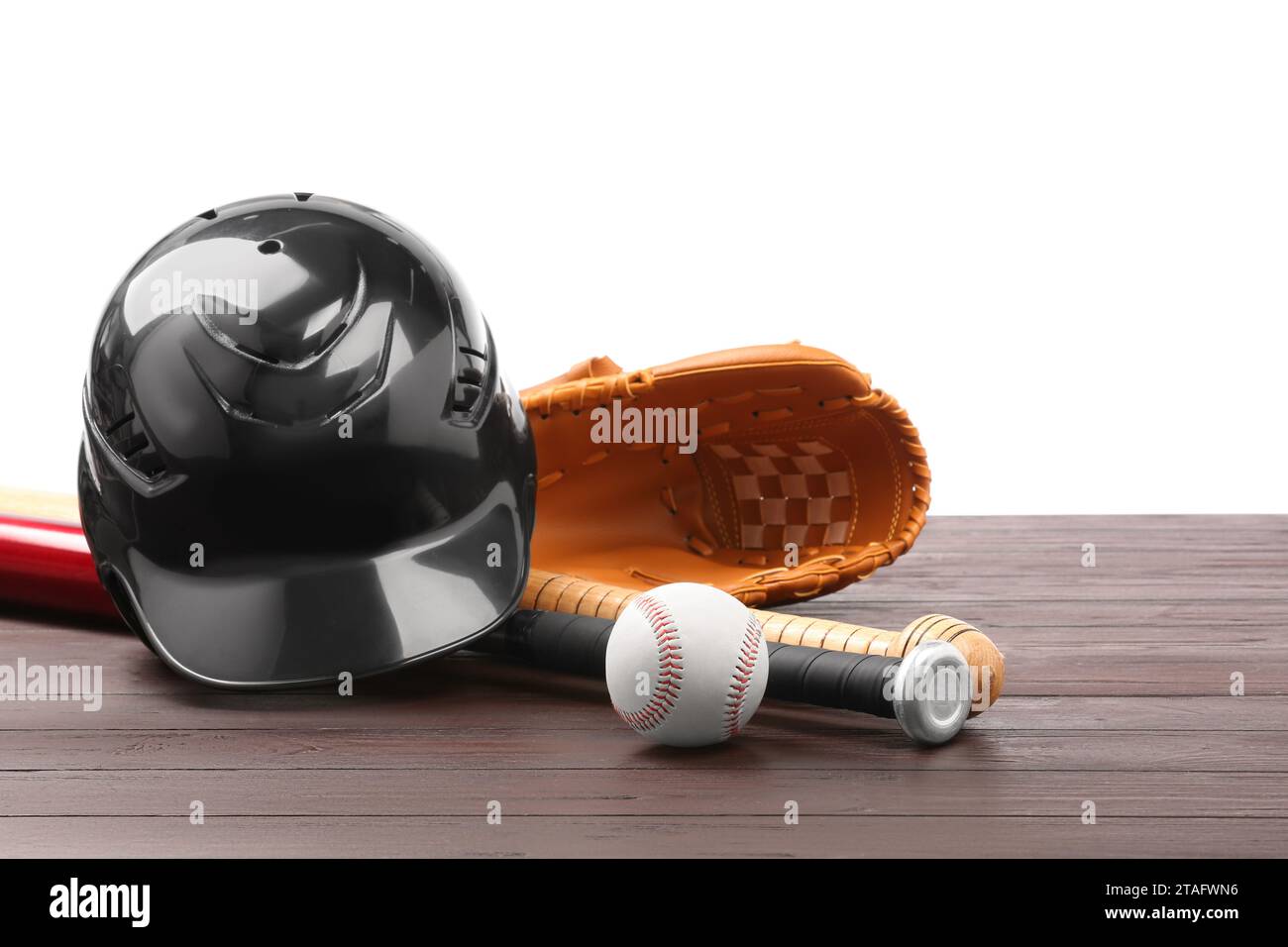 Baseball glove, bats, ball and batting helmet on wooden table against ...