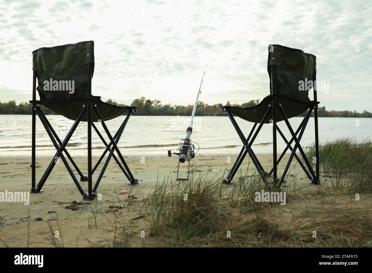 Folding chairs and fishing rod at riverside Stock Photo - Alamy