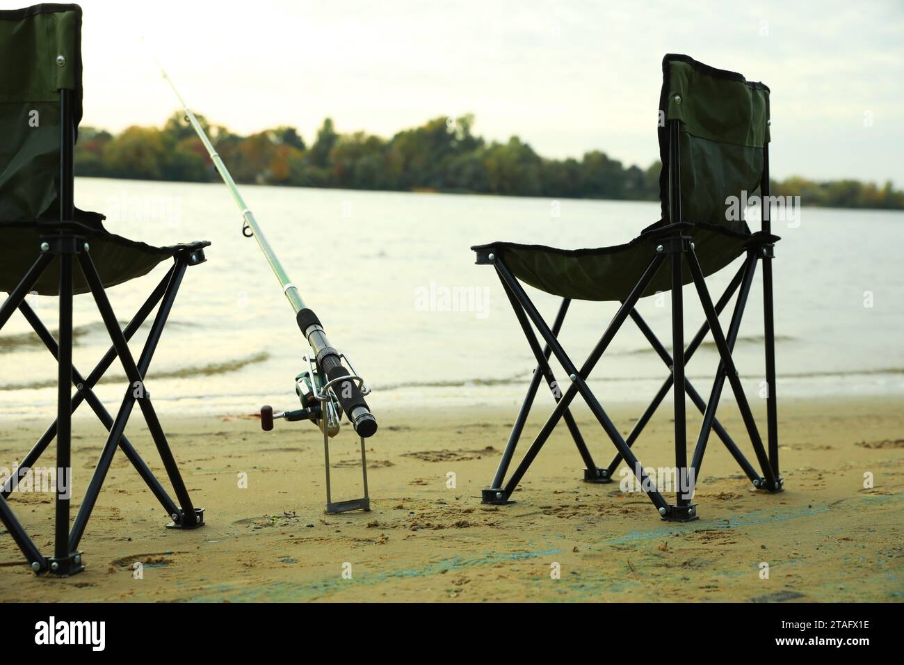 Folding chairs and fishing rod at riverside Stock Photo - Alamy