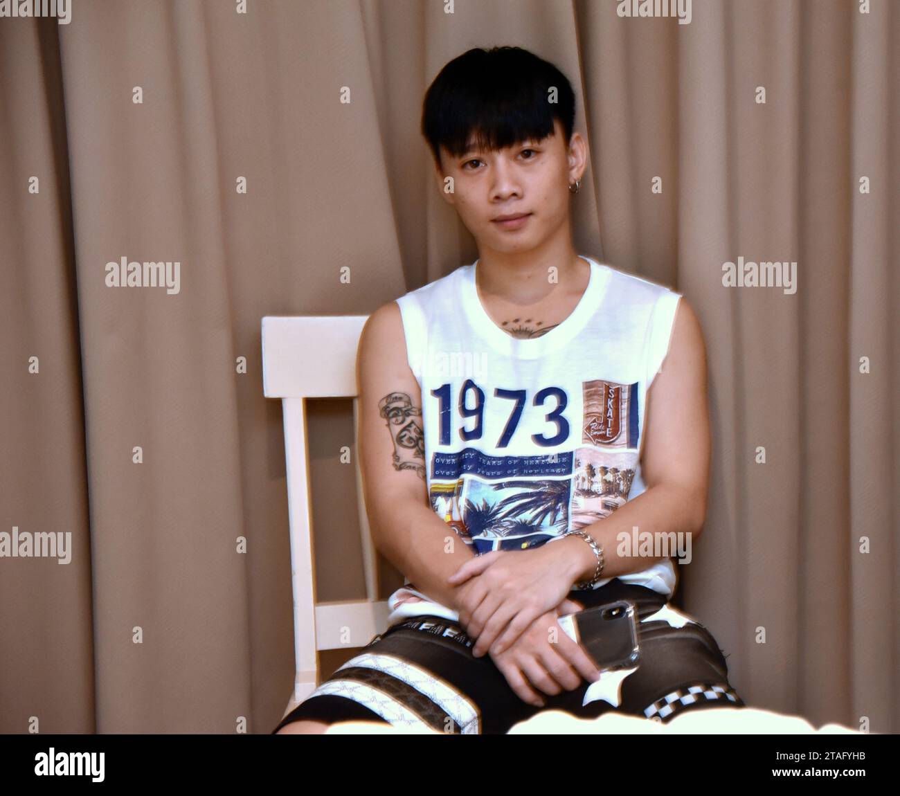 handsome, young male footballer from Northern Thailand sitting on chair ...