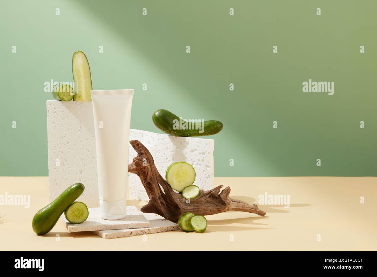 Empty cosmetic tube decorated with cucumber and props on a pastel ...