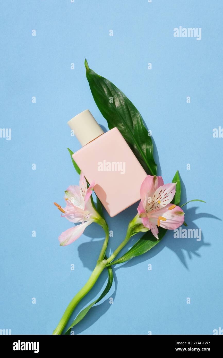 A light pink perfume bottle without a label is showcased with fresh ...