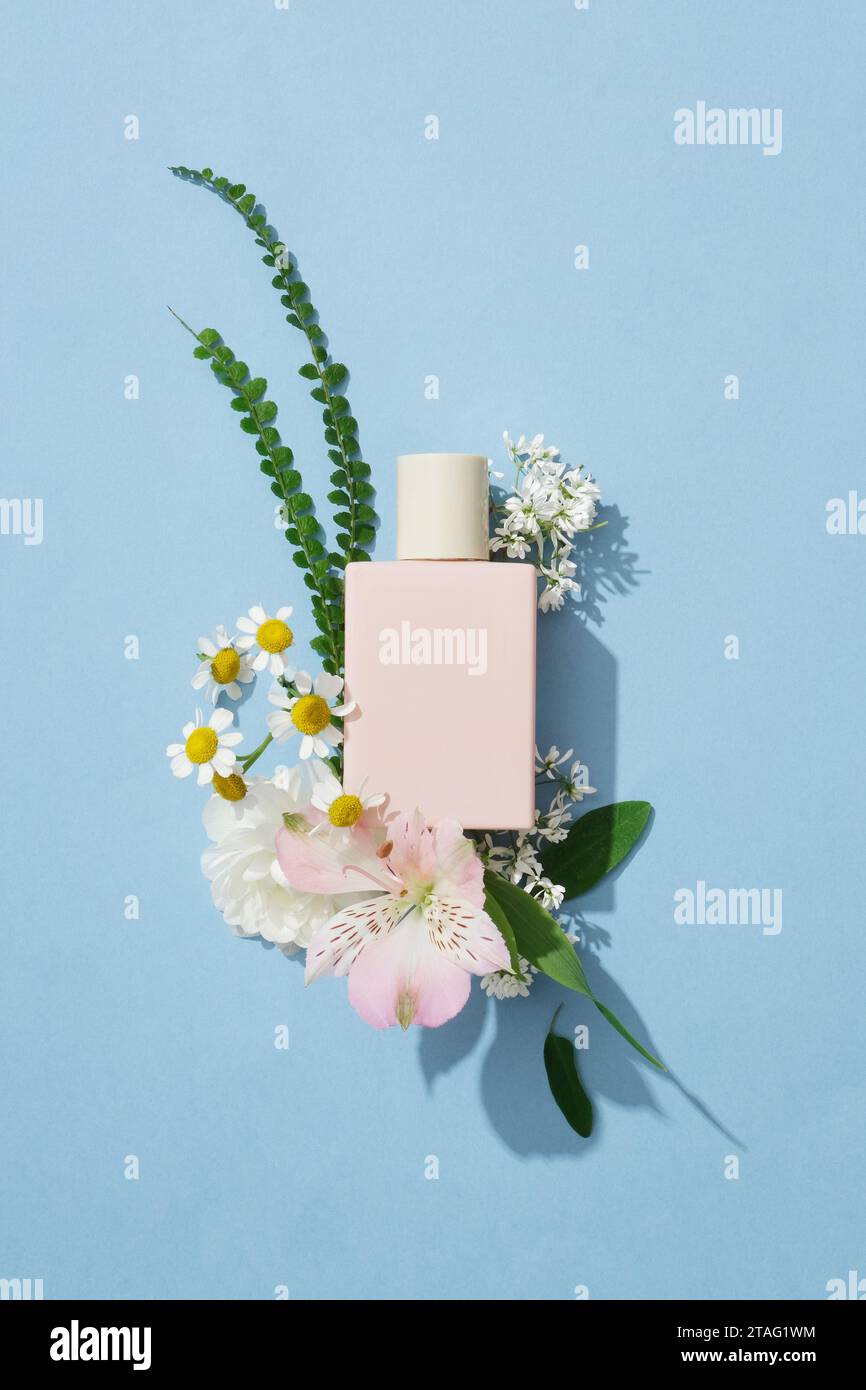 The labelless light pink perfume bottle is displayed with fresh flowers ...