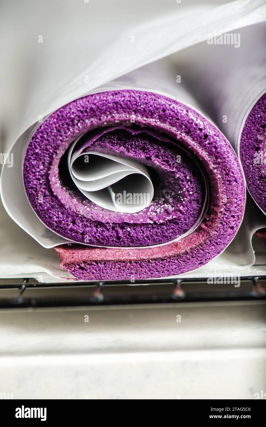 In the kitchen behind the scenes showing a baked Ube Swiss Roll cake ...