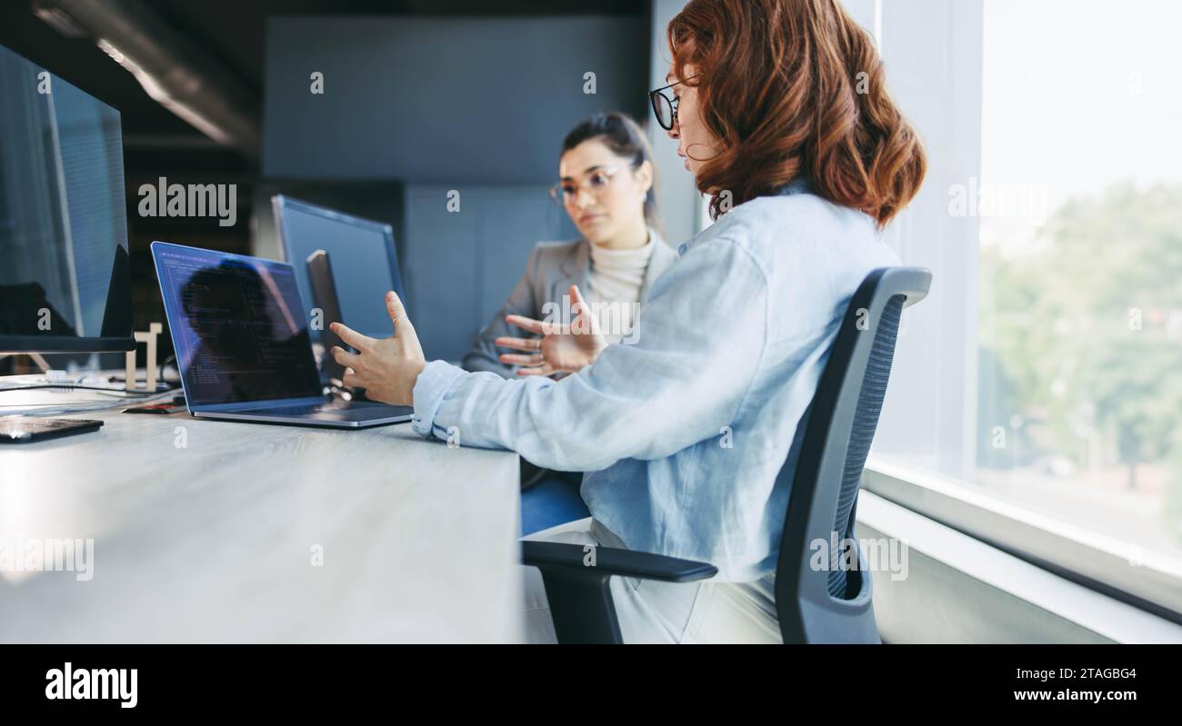Female Colleagues Actively Collaborate In A Modern Office Engaging In Discussions Coding And