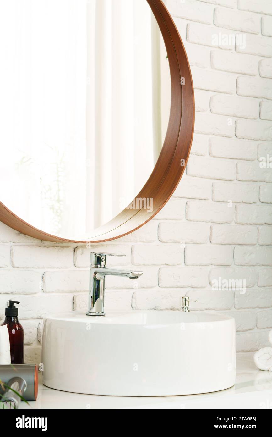 Bathroom interior with circle shaped mirror in wooden frame and white ...
