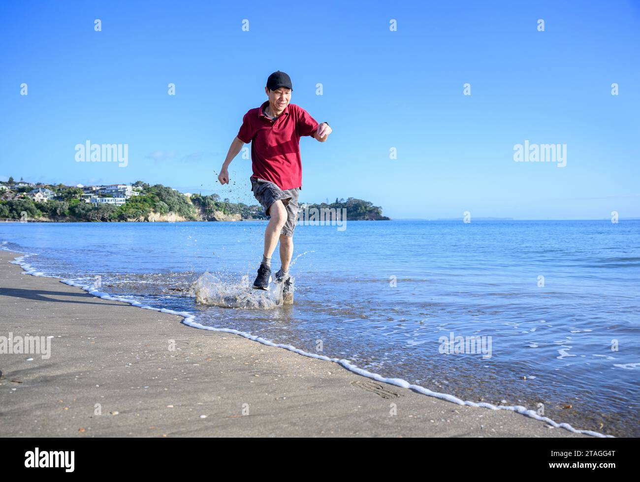 Man running in water on Milford Beach. Auckland Stock Photo - Alamy