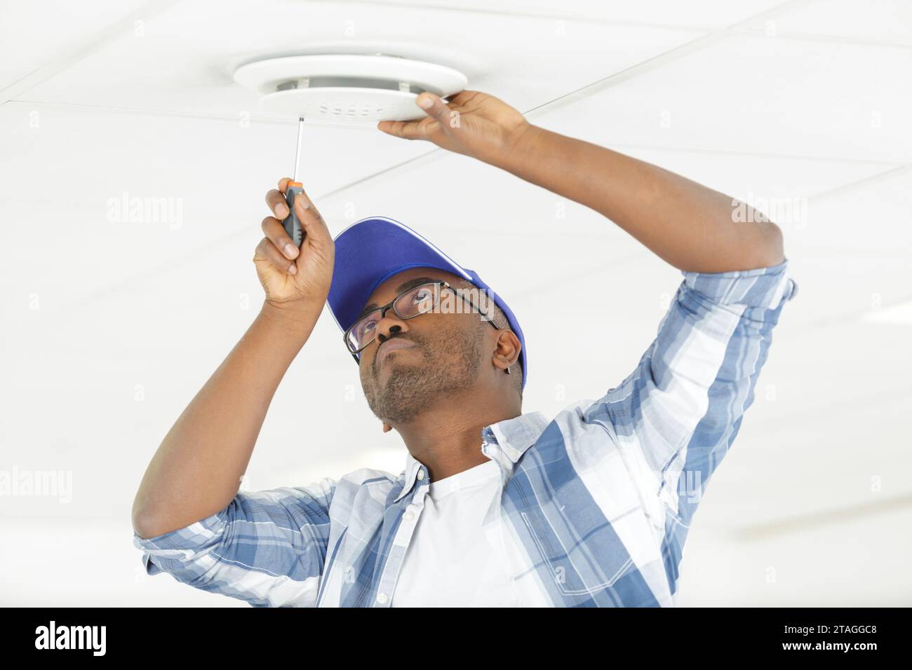 man fitting safety detector to ceiling Stock Photo - Alamy