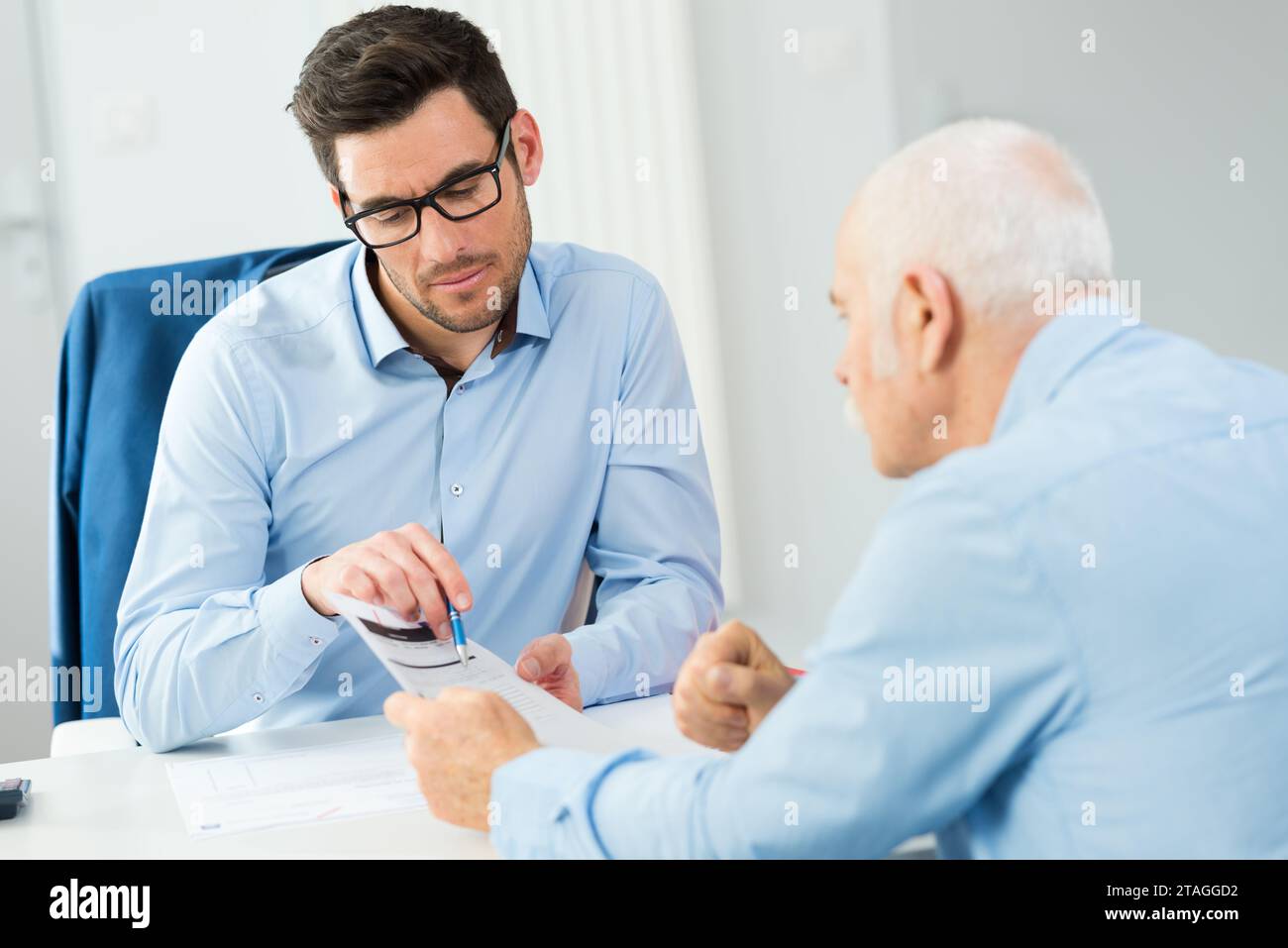 two men in business meeting looking at paperwork Stock Photo - Alamy