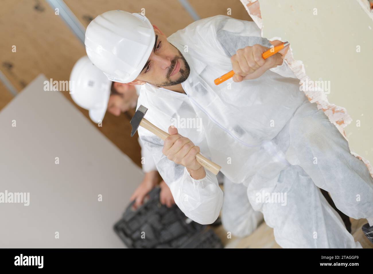 man hitting wall with hammer and opening a hole Stock Photo - Alamy