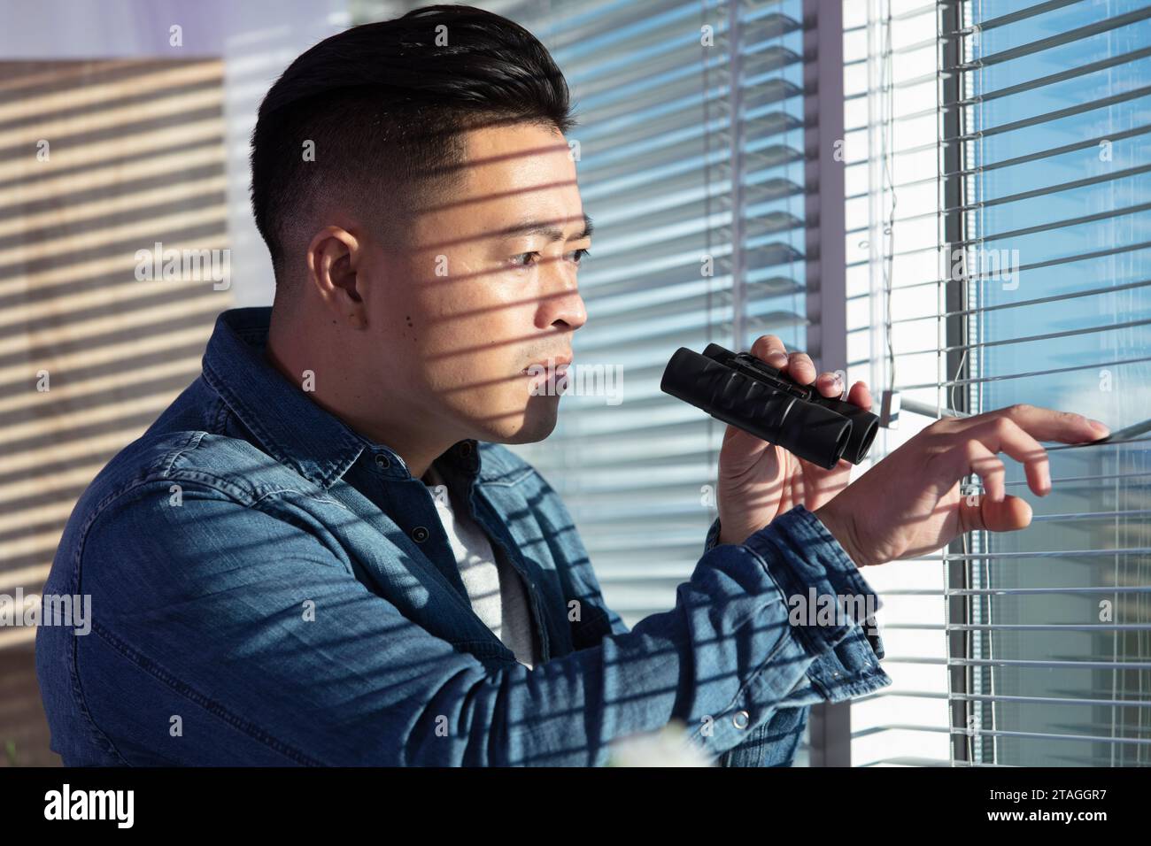 man looking through window blinds with binoculars Stock Photo - Alamy