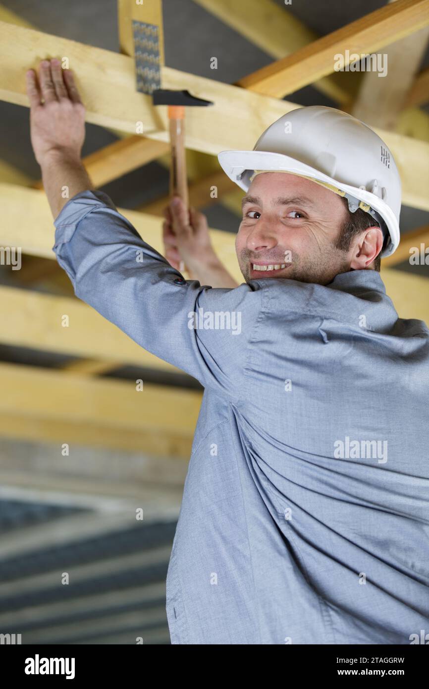 happy man builder hammer wood structure indoors Stock Photo - Alamy