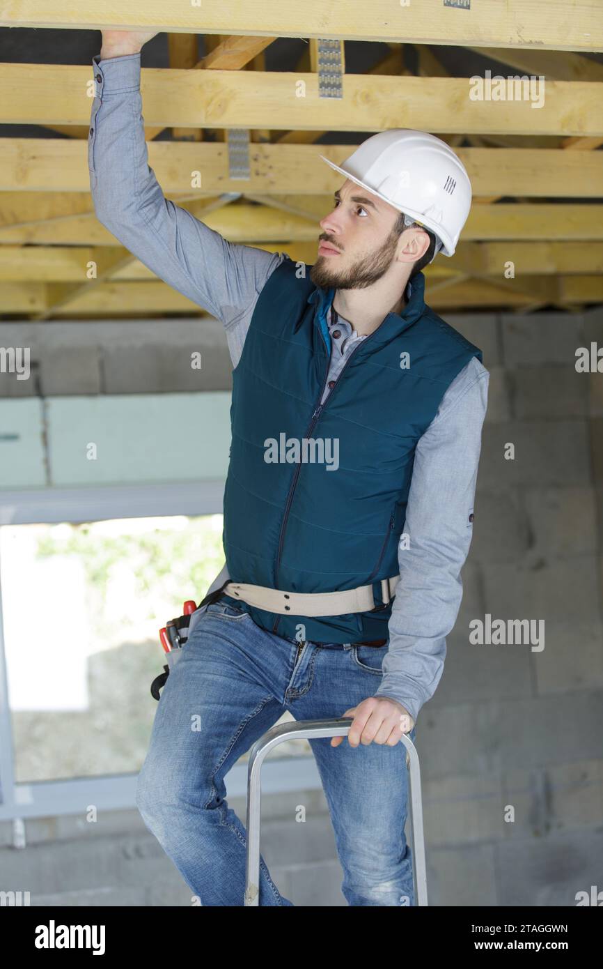 worker wearing coveralls and hard hat checks wooden beams Stock Photo ...