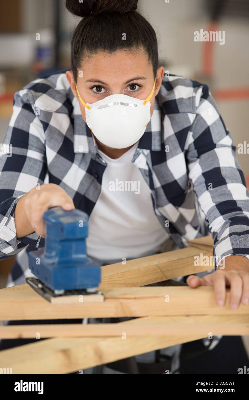 young carpenter wearing filter mask sanding wooden work piece Stock ...