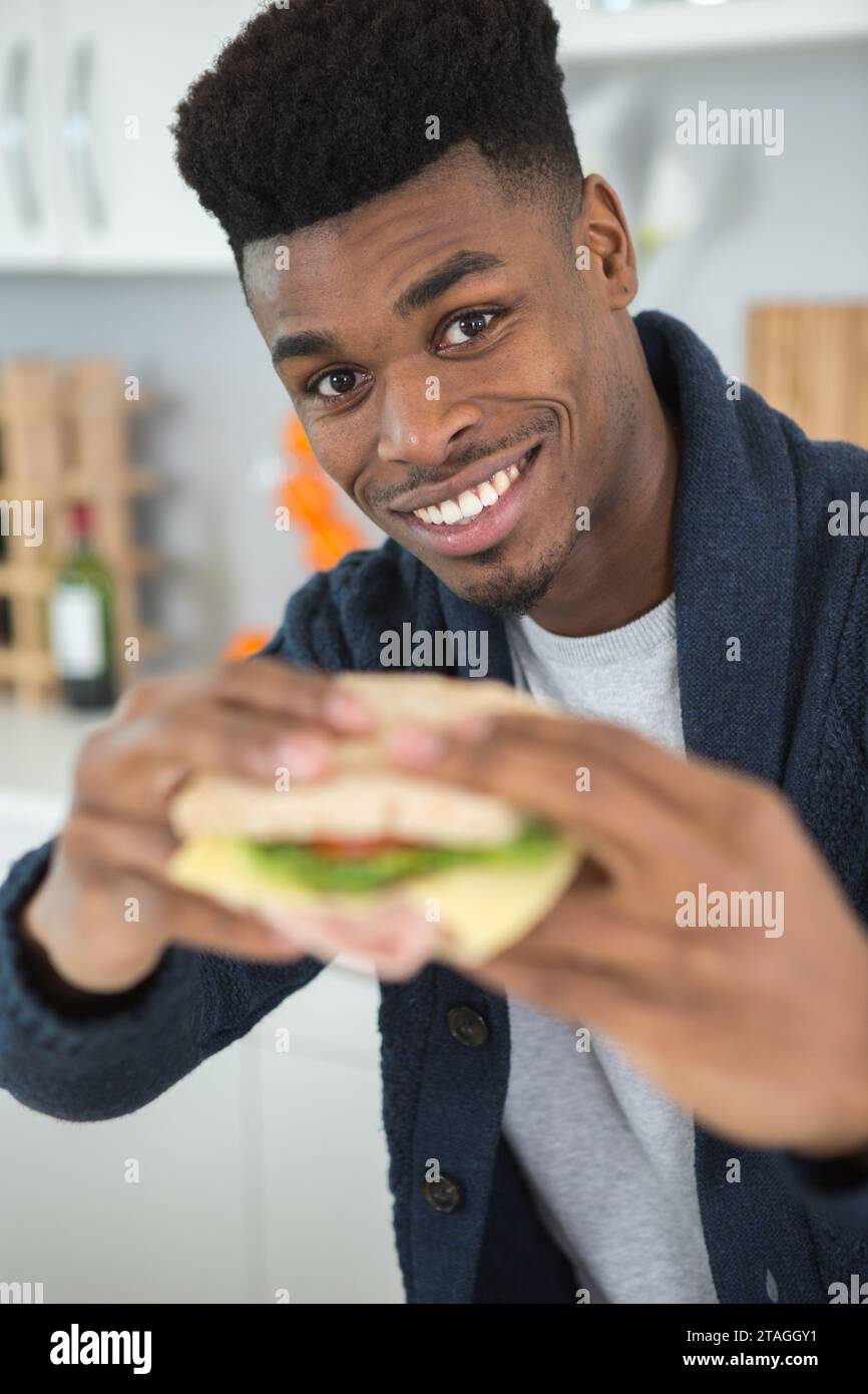 man holding a double sandwich on a black background Stock Photo - Alamy